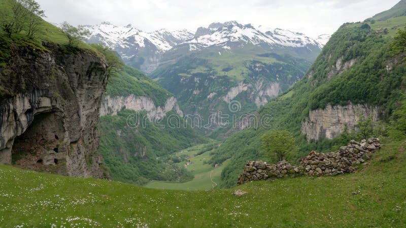 Scenic Valley View with Green Fields, Cliffs, and Snow-capped Mountains ...