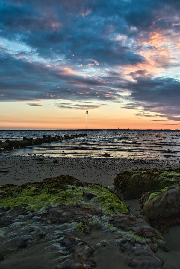 Scenic Vertical Shot of a Beach with Big Rocks during a Dramatic Sunset ...