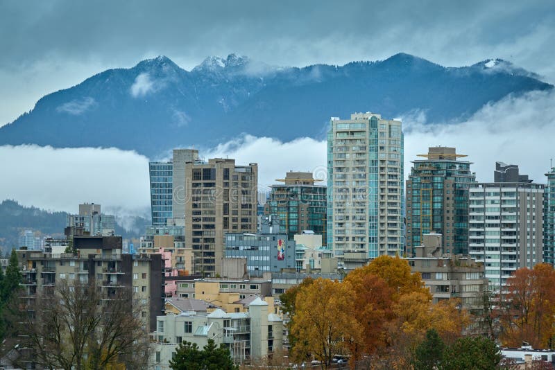 Scenic View of Buildings and Trees Against a Mountain Range Covered ...