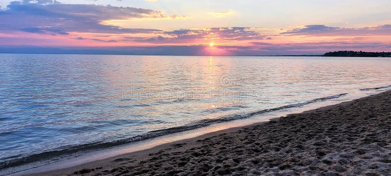 Scenic View of a Sea Shore at Sunset with the Sun Reflecting on the ...
