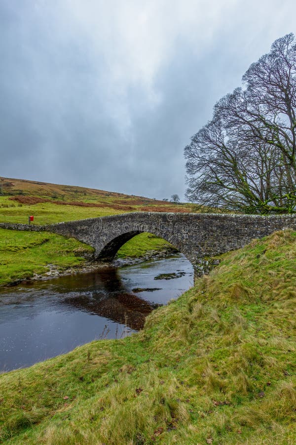 A Scenic View of a Stone Bridge Over a River with Grassy Slope Under a ...