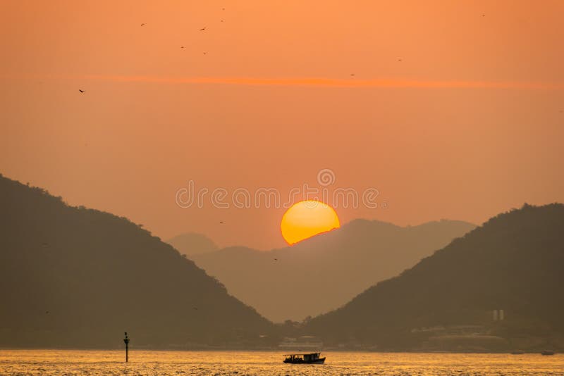 Scenic View of a Sunrise Behind a Mountain Range, and a Boat on the ...