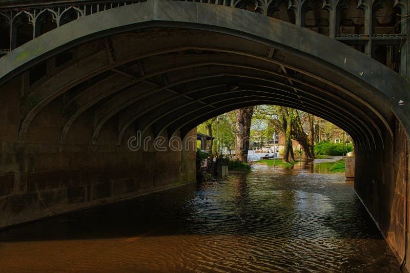 Scenic View Under an Old Stone Bridge with Intricate Arches, Reflecting ...