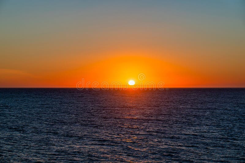 Scenic View of a Vibrant Red Cloudless Sunset Reflected on the Calm Sea ...