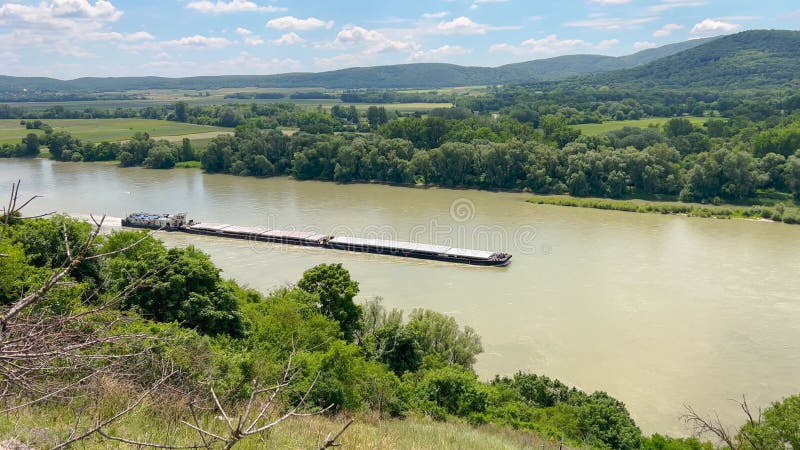 A Scenic View of a Wide River with a Barge Sailing through, Surrounded ...