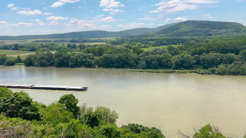 A Scenic View of a Wide River with a Barge Sailing through, Surrounded ...