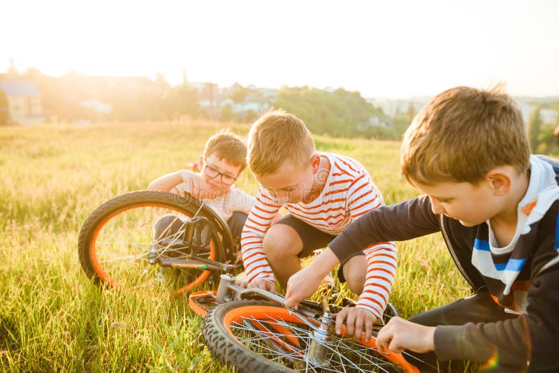School-age Boys Ride a Bicycle in a Meadow. Stock Image - Image of ...