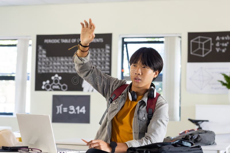 In School, Asian Teenage Boy Raising Hand while Using Laptop in ...