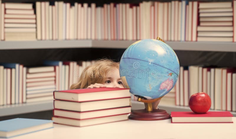School Kid Looking at Globe in Library at the Elementary School. Child ...