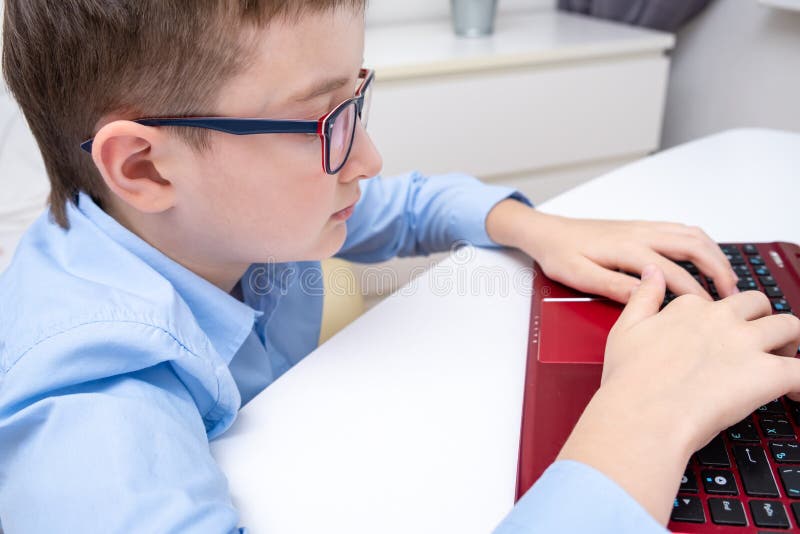 A School Boy Sitting by the Table with a Laptop and Doing Homework, E ...
