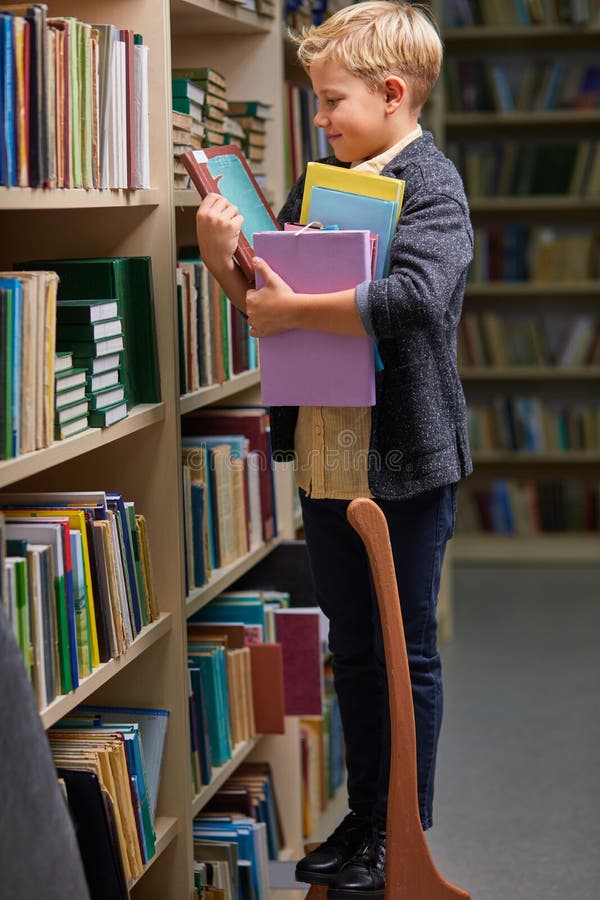 Little School Boy Taking Books from Shelves in Library, with a Stack of ...