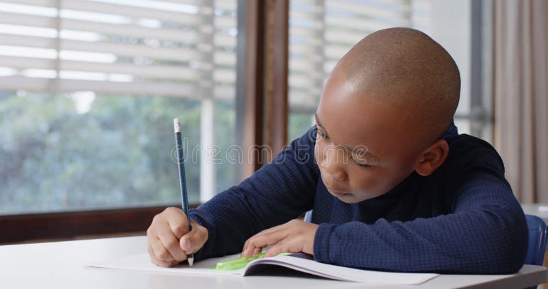 In School, Boy Writing in Notebook, Concentrating on His Work Stock ...