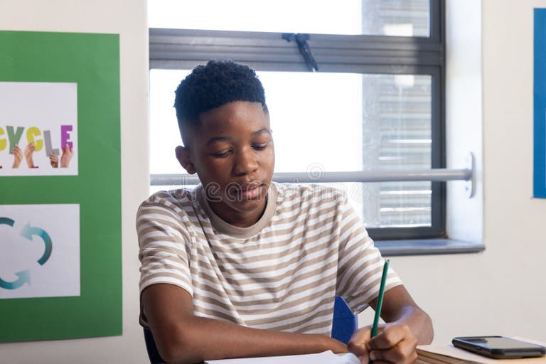 In School, Boy Writing in Notebook at Desk, Concentrating on Assignment ...