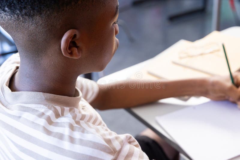 In School, Boy Writing in Notebook at Desk, Focusing on Assignment ...