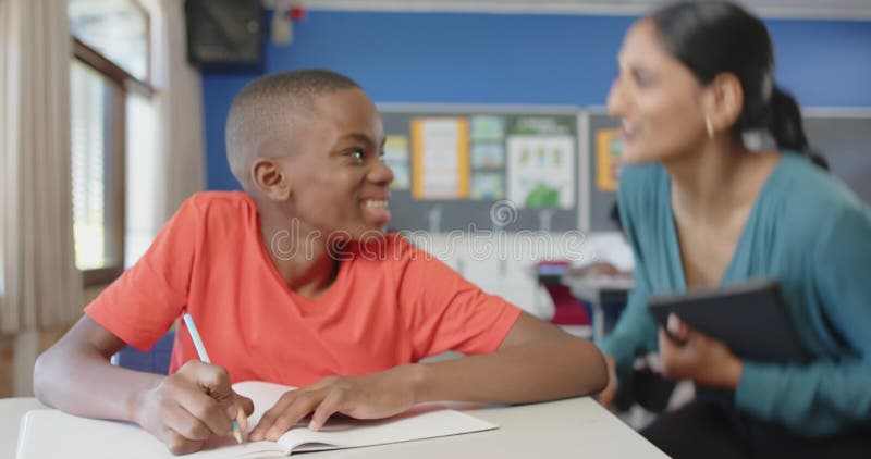 In School, Boy Writing in Notebook and Smiling while Talking To Teacher ...