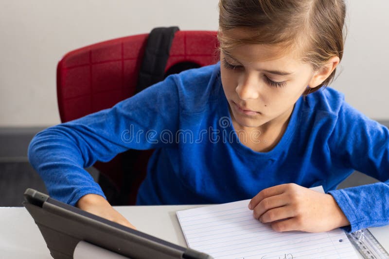 In School, Boy Writing in Notebook while Using Tablet in Classroom ...
