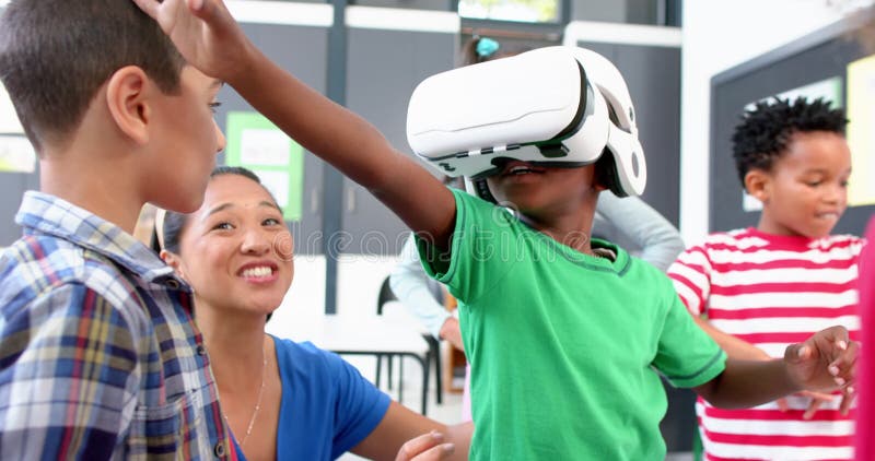 In School, Children Using VR Headset with Teacher Guiding Them in ...