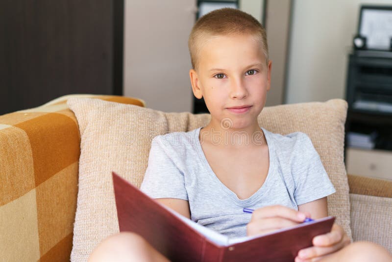 School Days, Boy Solves His Homework on Couch with a Notebook in His ...