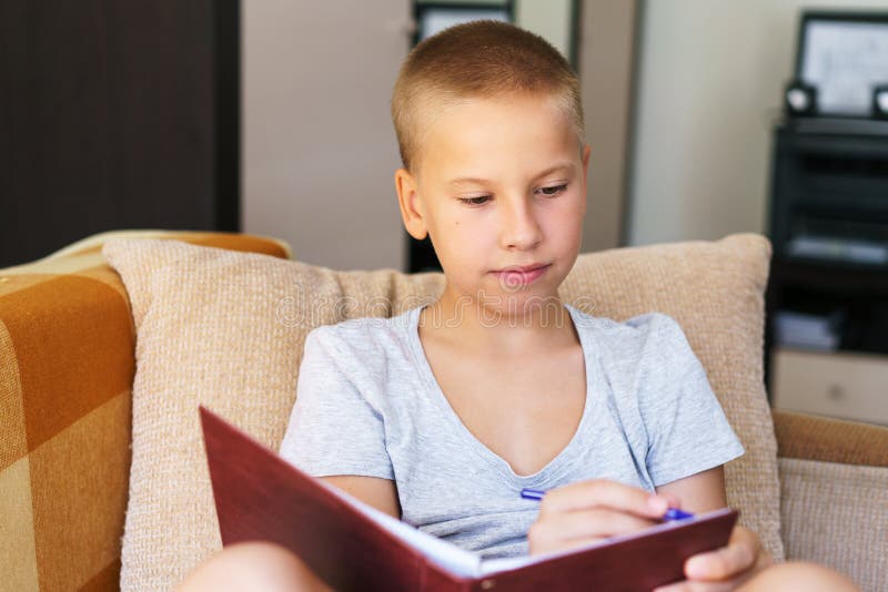 School Days, Boy Solves His Homework on Couch with a Notebook in His ...