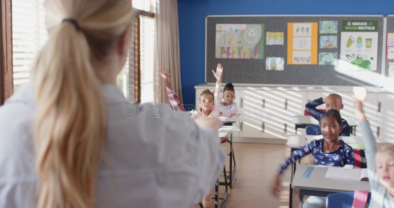 In School, Female Teacher Calling on Students Raising Hands in ...