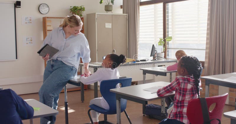 In School, Female Teacher Interacting with Students in Classroom ...
