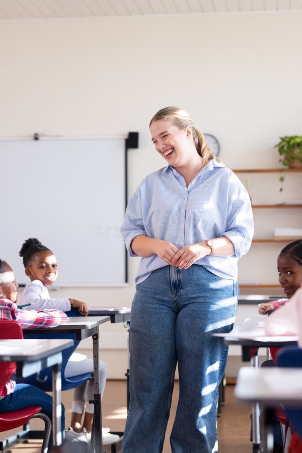 In school, female teacher smiling and engaging with diverse students in ...