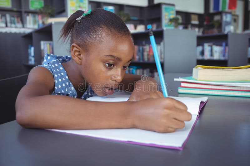 In School, Focused Girl Writing in Notebook at Library Table ...
