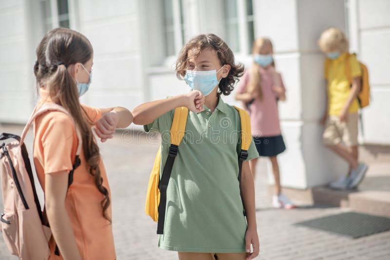 Friends in Protective Masks in the School Yard Greeting Each Other ...