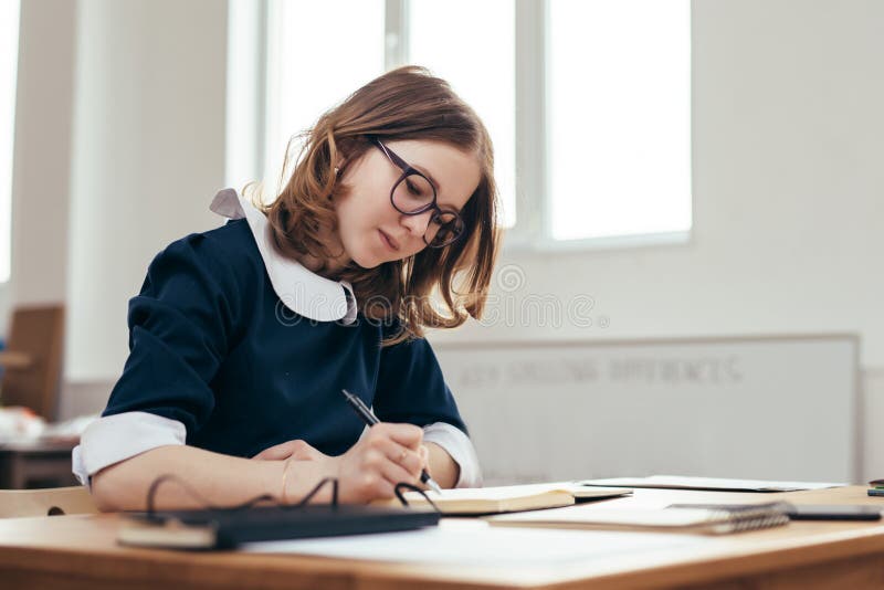School Girl Writes in a Notebook Sitting at Table Classwork, Homework ...