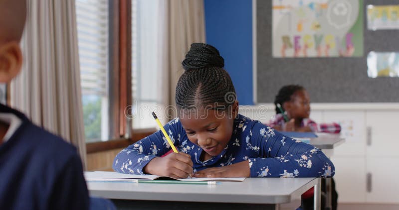 In School, Girl Writing in Notebook at Desk, Concentrating on Her Work ...