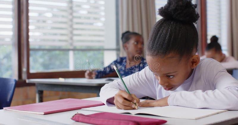 In School, Girl Writing in Notebook at Desk, Concentrating on Her Work ...