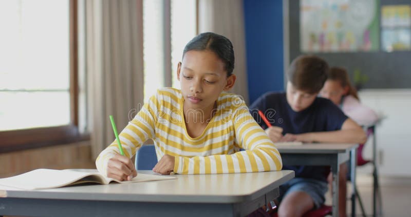 In School, Girl Writing in Notebook at Desk, Concentrating on Her Work ...