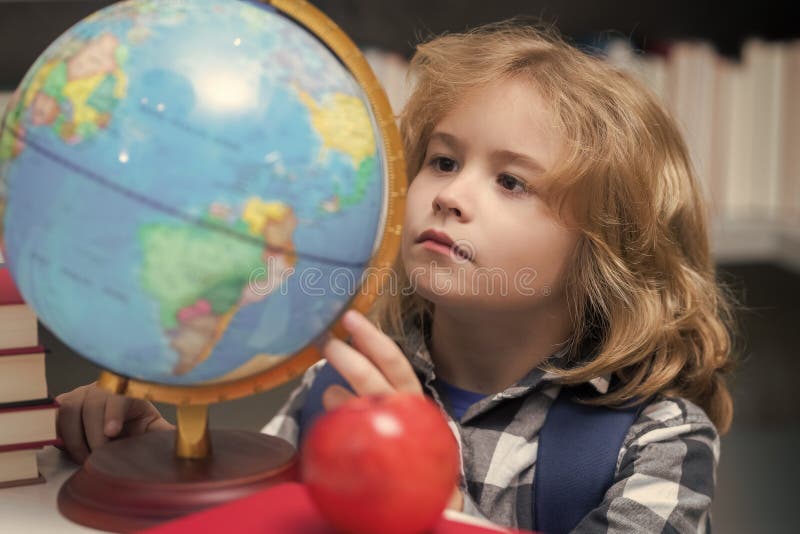 School Kid Looking at Globe in Library at the Elementary School. Child ...