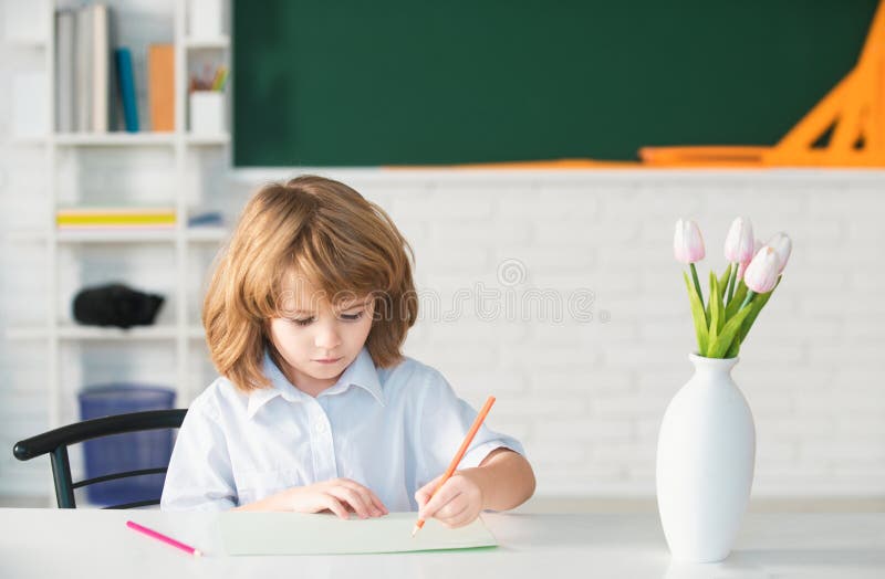 School Kid Writing in Copybook and Sitting at Table in Classroom. First ...