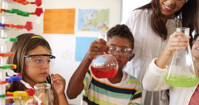 Teacher Assisting School Kids in Doing Experiment in Classroom Stock ...