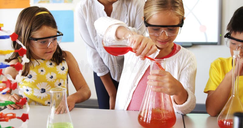 Teacher Assisting School Kids in Doing Experiment in Classroom Stock ...