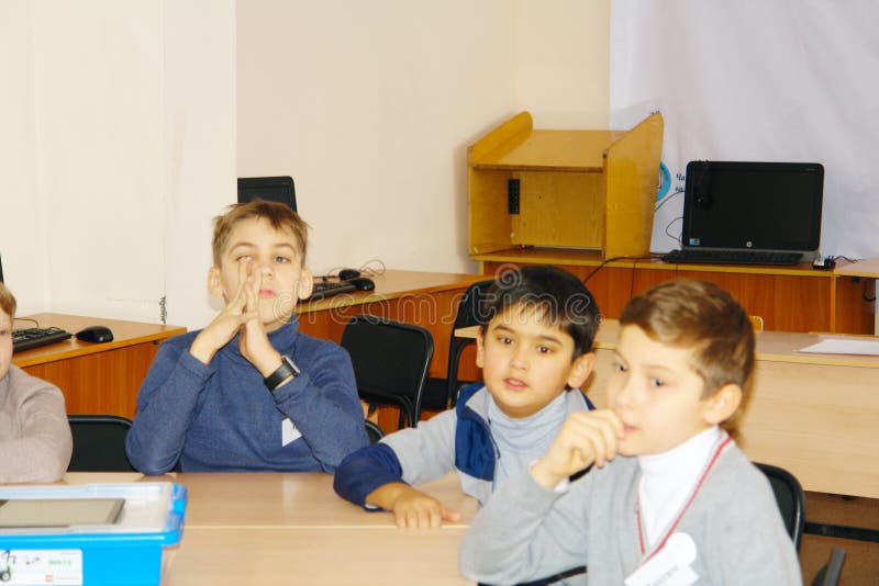 School Kids In The Classroom Sitting At Their Desks And Listen To The ...