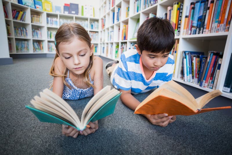 School Kids Lying on Floor and Reading a Book in Library Stock Photo ...
