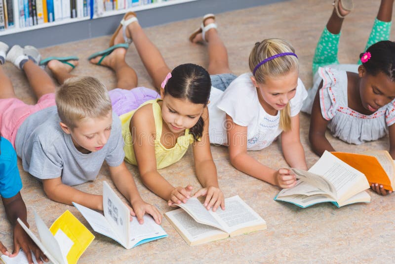 School Kids Lying on Floor Reading Book in Library Stock Image - Image ...