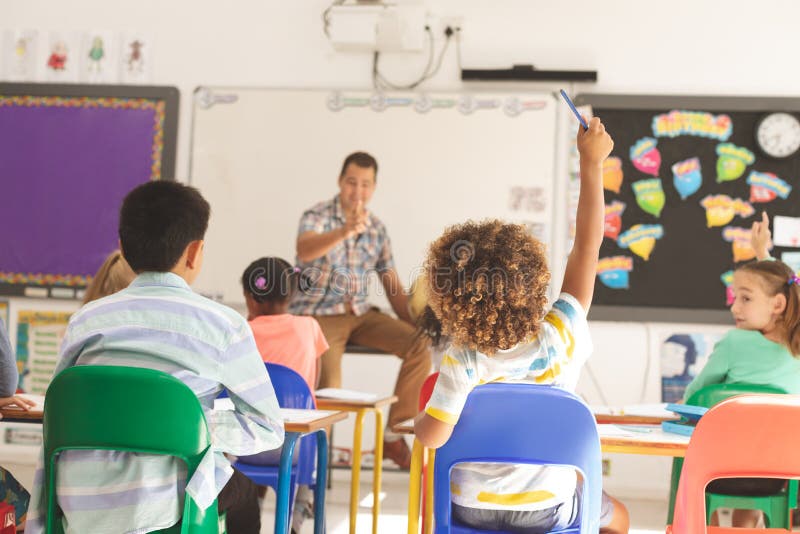 School Kids Raising Hand while Teacher Asking Question in Classroom at ...