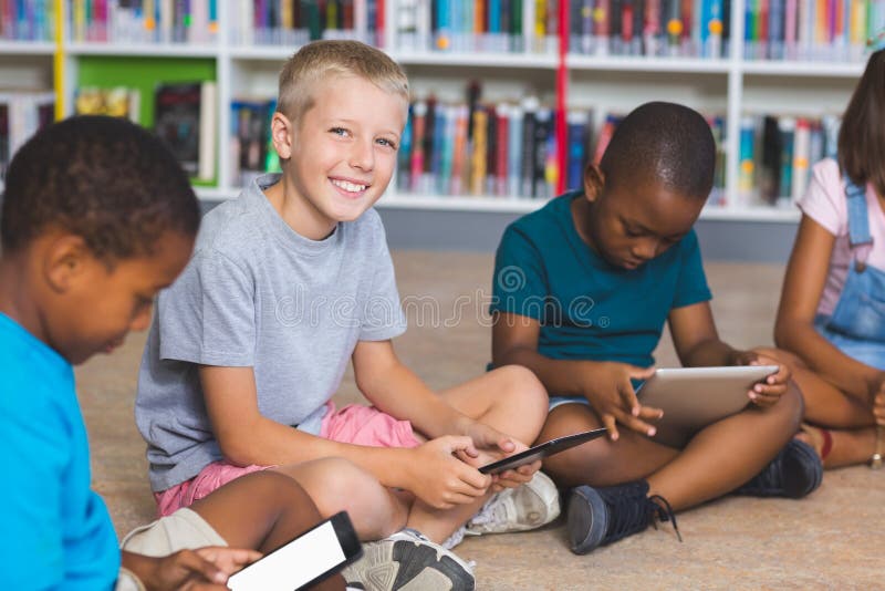 School Kids Sitting on Floor Using Digital Tablet in Library Stock ...