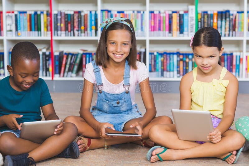 School Kids Sitting on Floor Using Digital Tablet in Library Stock ...