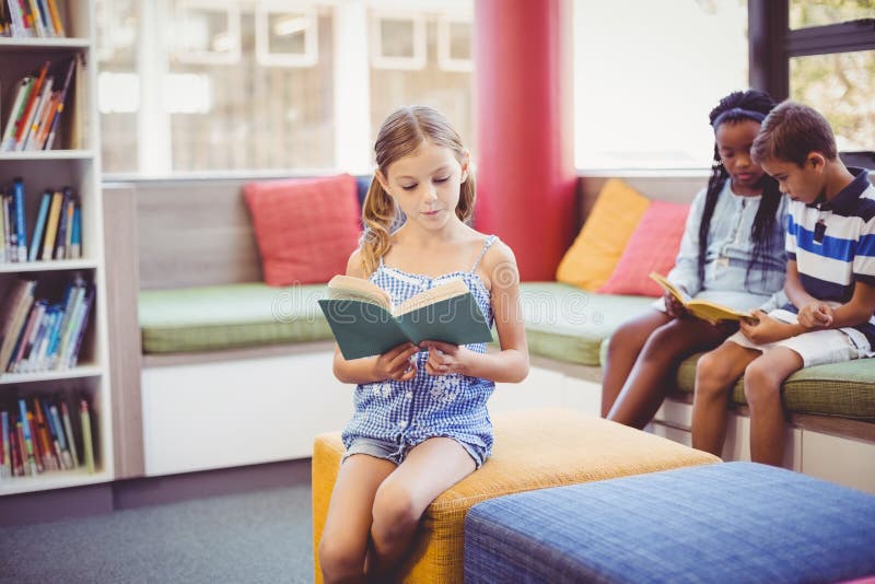 School Kids Sitting on Sofa and Reading Book in Library Stock Image ...