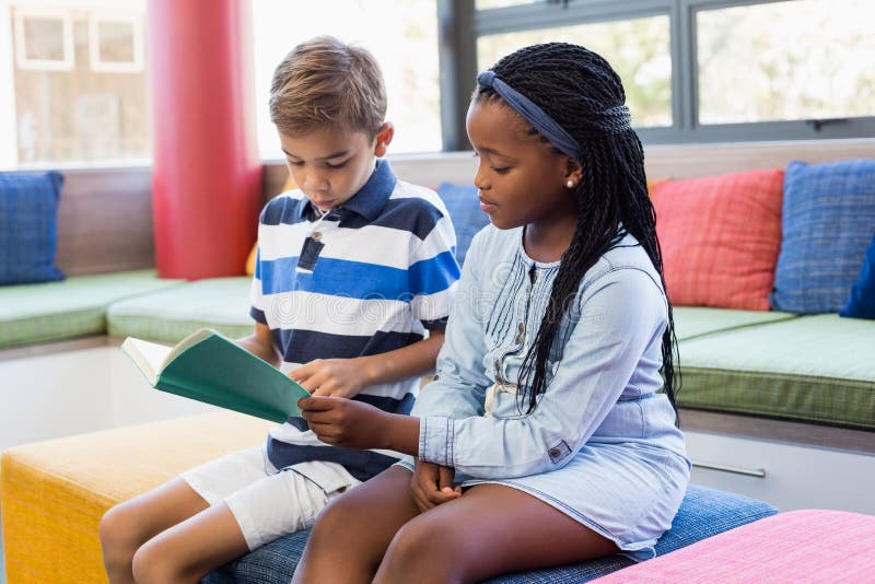 School Kids Sitting Together on Sofa and Reading a Book Stock Photo ...