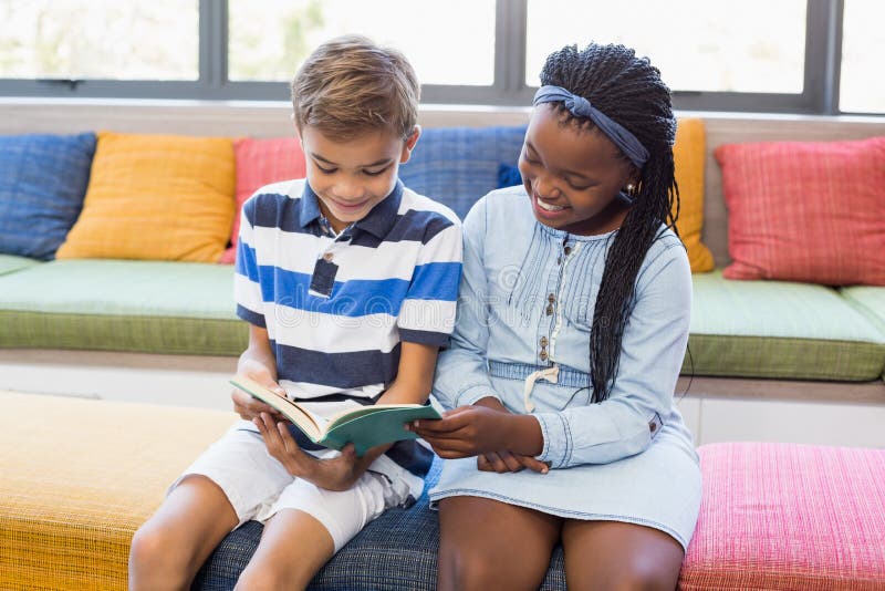 School Kids Sitting Together on Sofa and Reading Book Stock Image ...