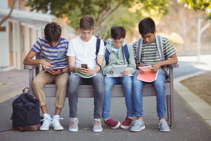 School Kids Using Mobile Phone and Digital Tablet on Bench Stock Photo ...