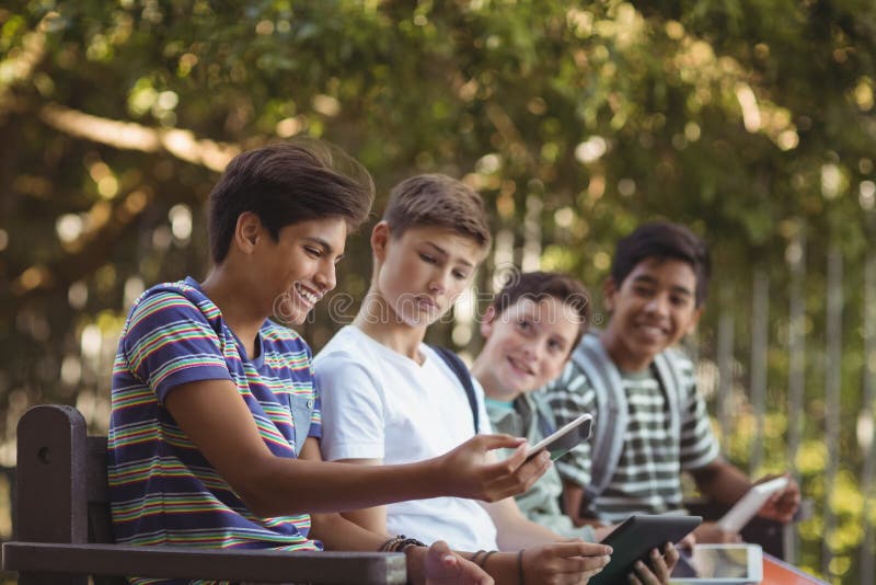 School Kids Using Mobile Phone and Digital Tablet on Bench Stock Photo ...