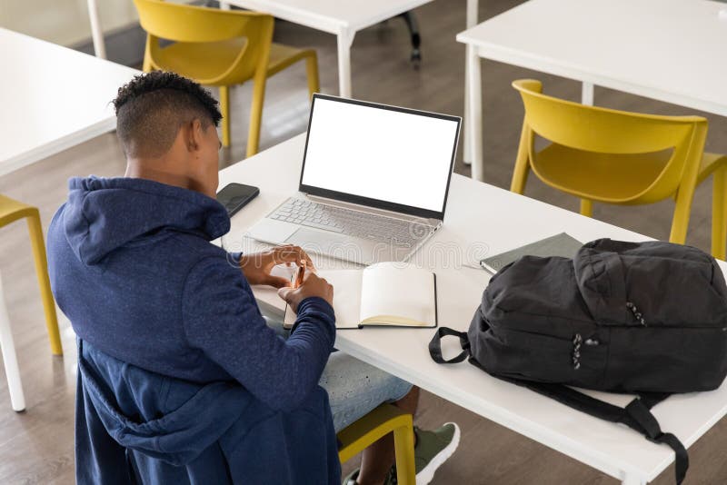In School, Male Student Using Smartphone and Laptop while Sitting at ...
