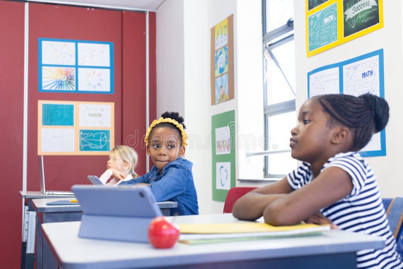 In School, Multiracial Girls Using Tablets and Laptops while Sitting at ...