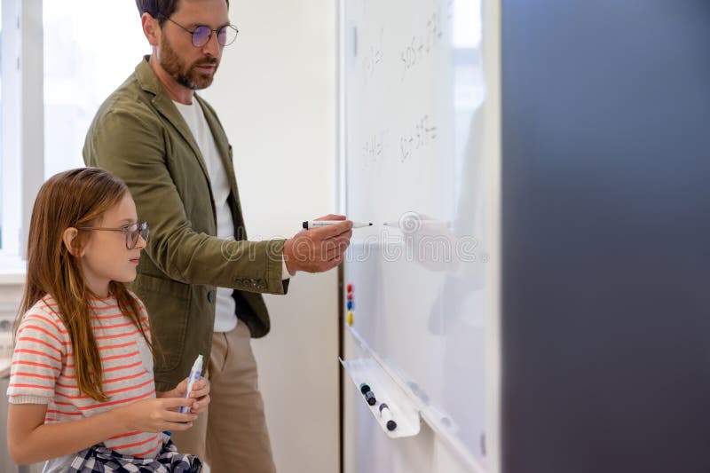 School Teacher Watching Pupil Writing on White Board in Classroom ...